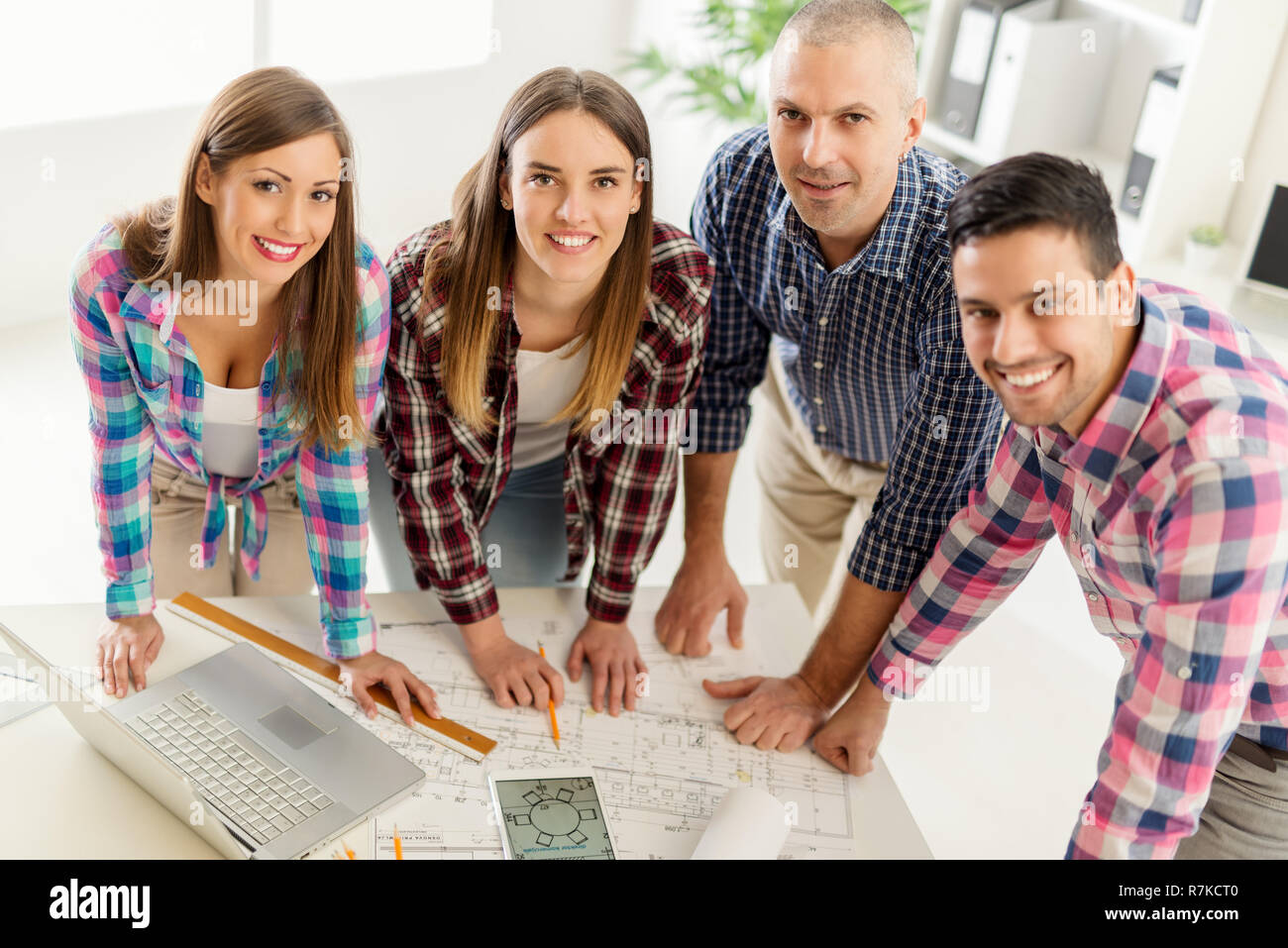 Happy four designer people looking project on computer Stock Photo - Alamy
