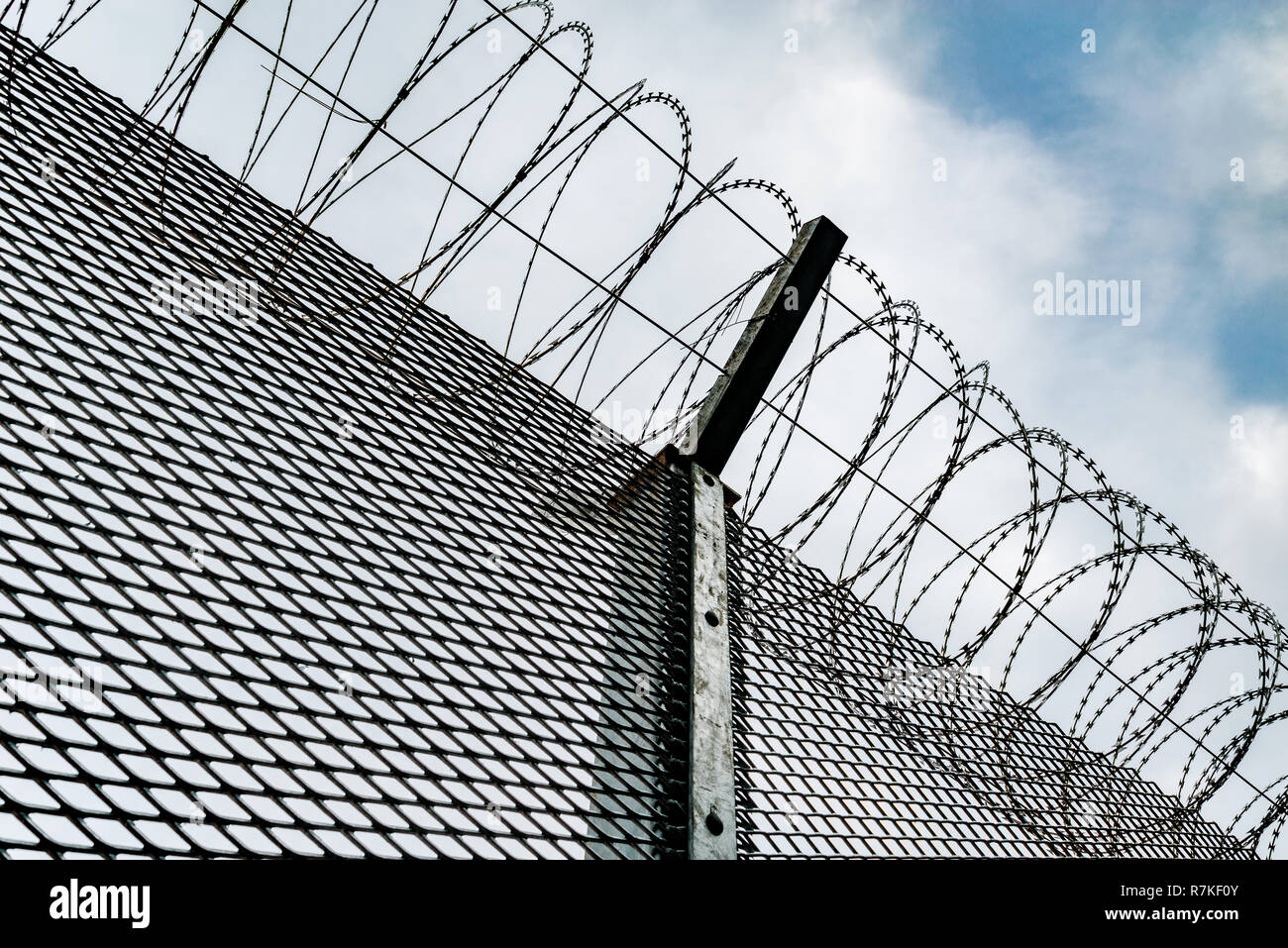 Metal fence with barbed wire in the prison Stock Photo - Alamy