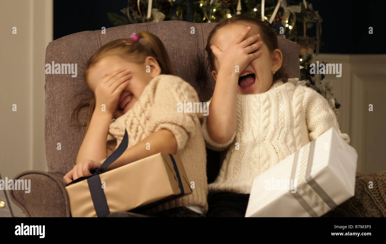 Girls play hiding game closing their faces with hands. Christmas kids ...