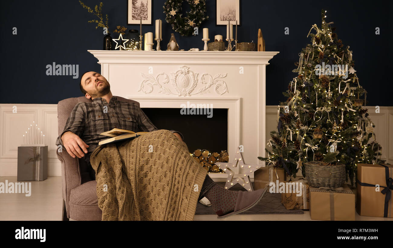 Young man sleeping in a chair on Christmas evening. Boring christmas ...