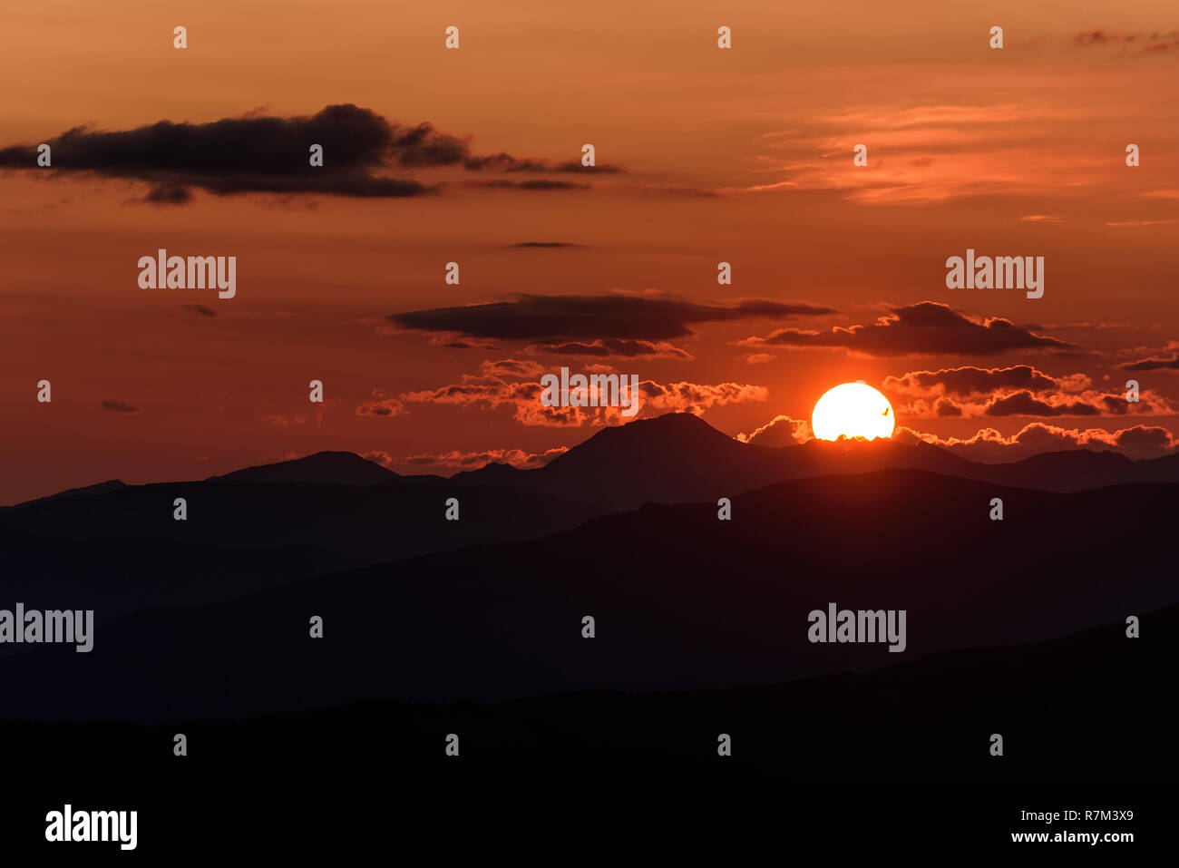 Colorful landscape with a circular disc of the sun and clouds over the ...