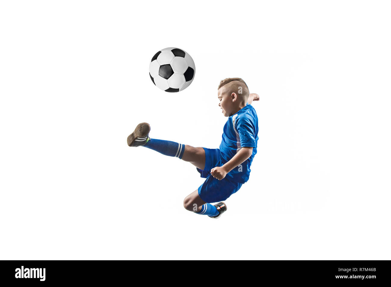 Young boy with soccer ball doing flying kick, isolated on white ...