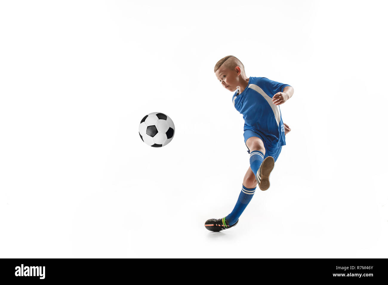 Young boy with soccer ball doing flying kick, isolated on white ...