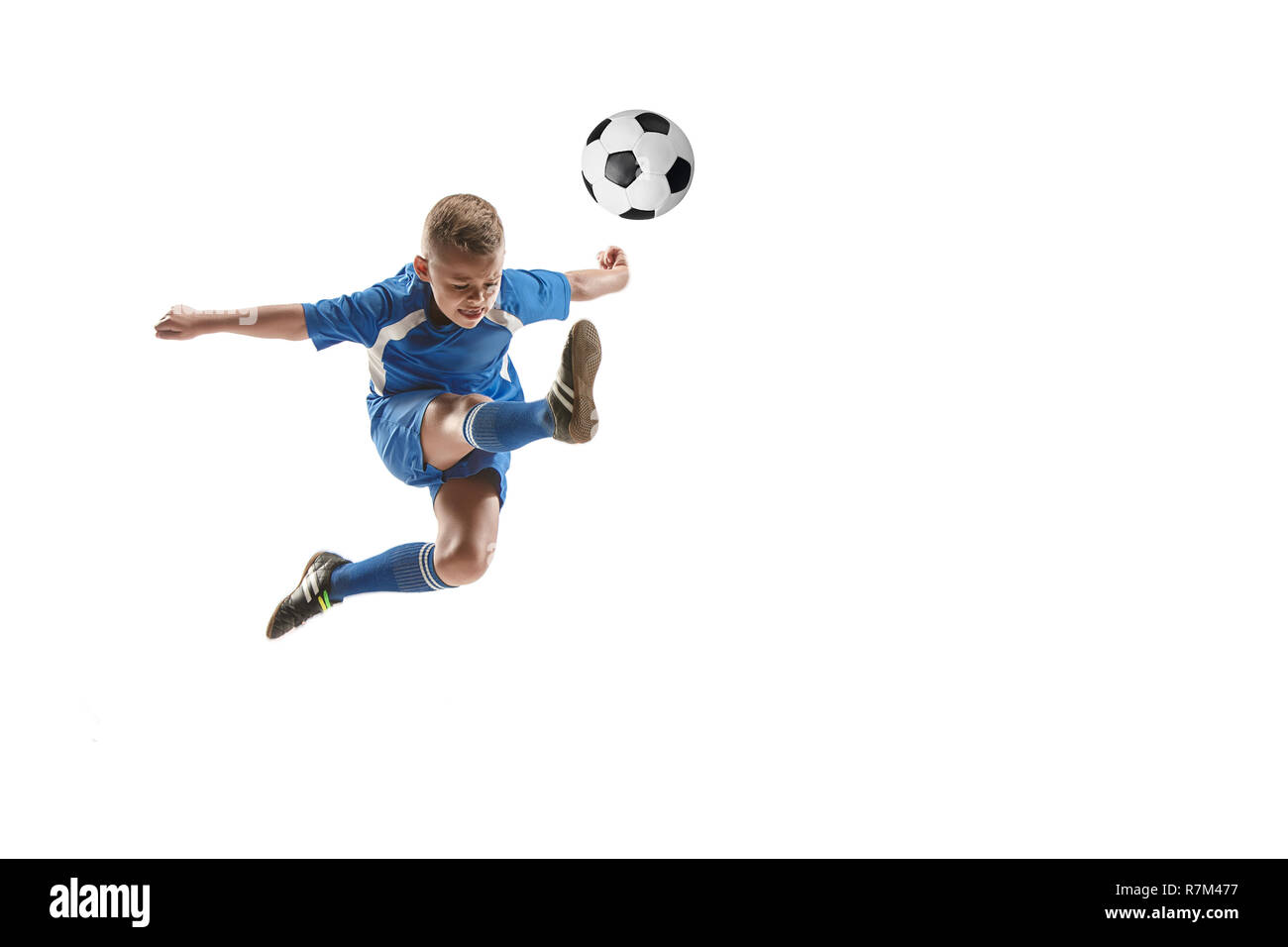 Young boy with soccer ball doing flying kick, isolated on white ...
