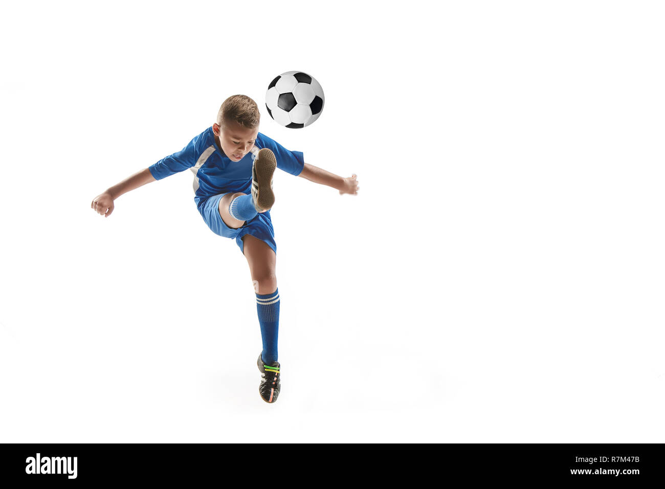 Young boy with soccer ball doing flying kick, isolated on white ...