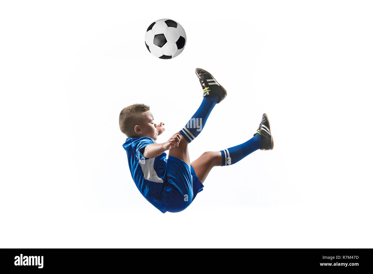 Young boy with soccer ball doing flying kick, isolated on white ...