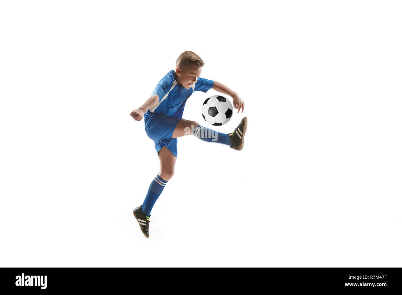 Young boy with soccer ball doing flying kick, isolated on white ...
