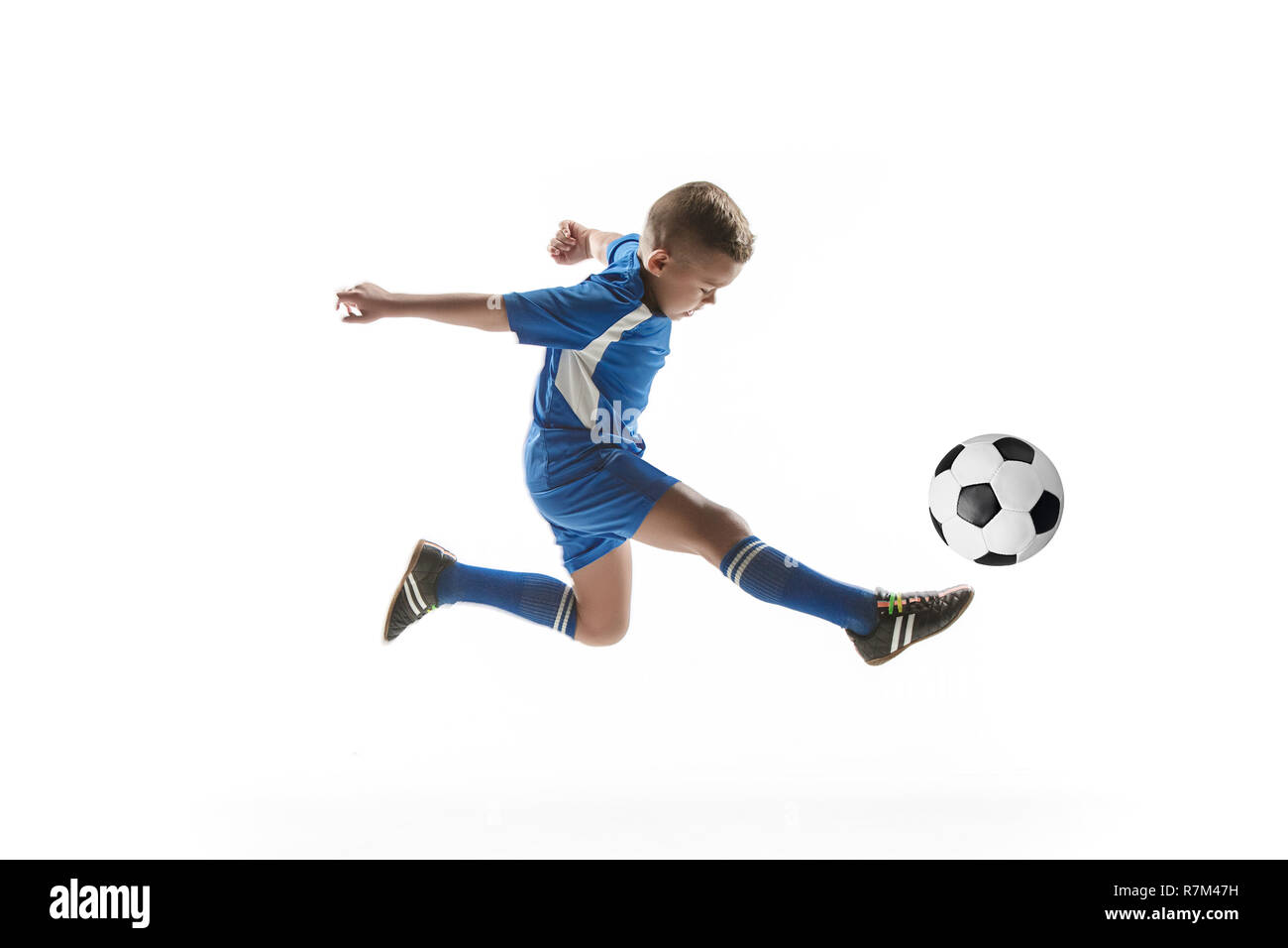 Young boy with soccer ball doing flying kick, isolated on white ...