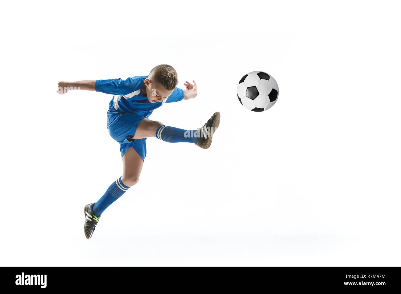 Young boy with soccer ball doing flying kick, isolated on white ...
