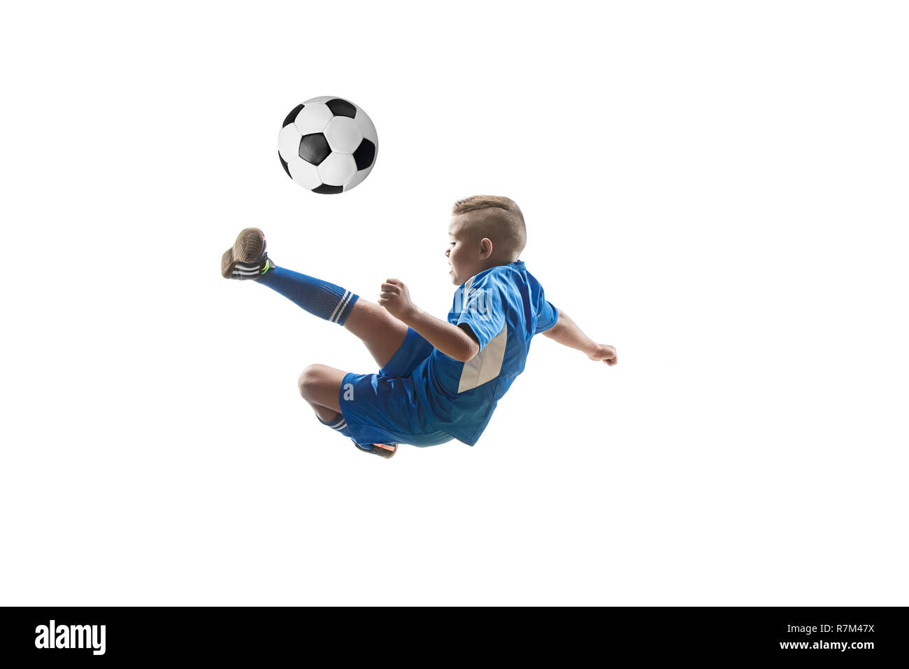Young boy with soccer ball doing flying kick, isolated on white ...