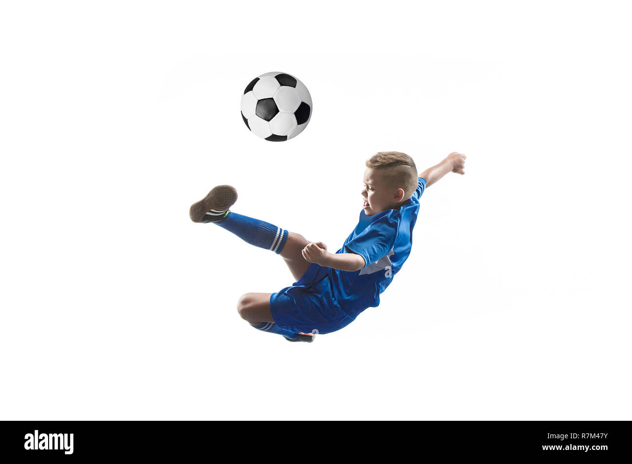 Young boy with soccer ball doing flying kick, isolated on white ...