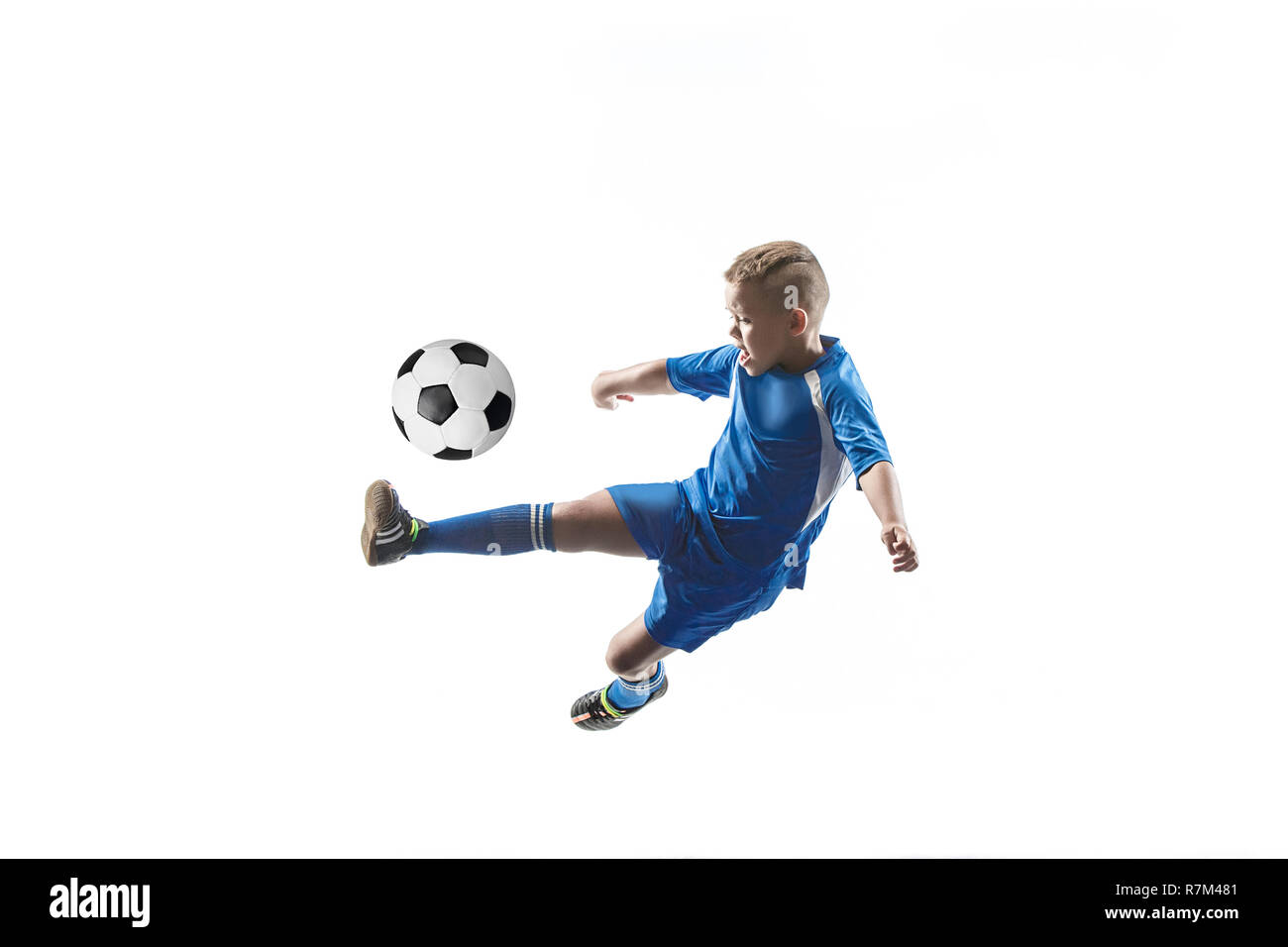 Young boy with soccer ball doing flying kick, isolated on white ...