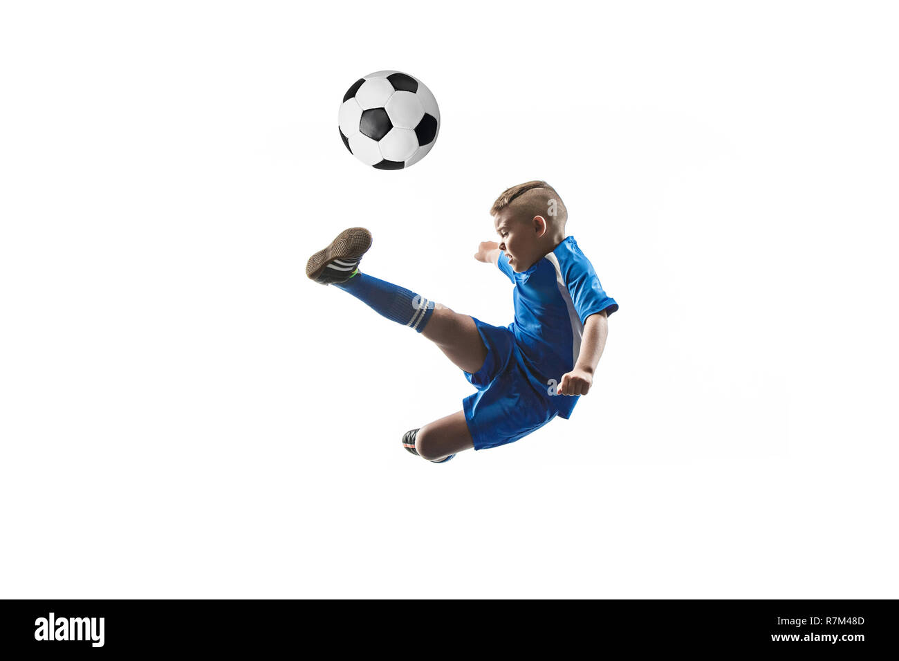 Young boy with soccer ball doing flying kick, isolated on white ...