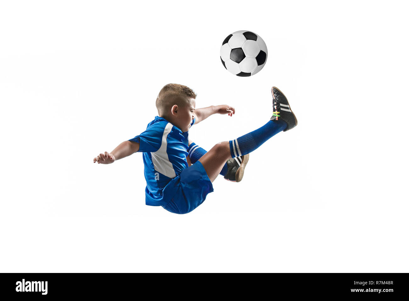 Young boy with soccer ball doing flying kick, isolated on white ...