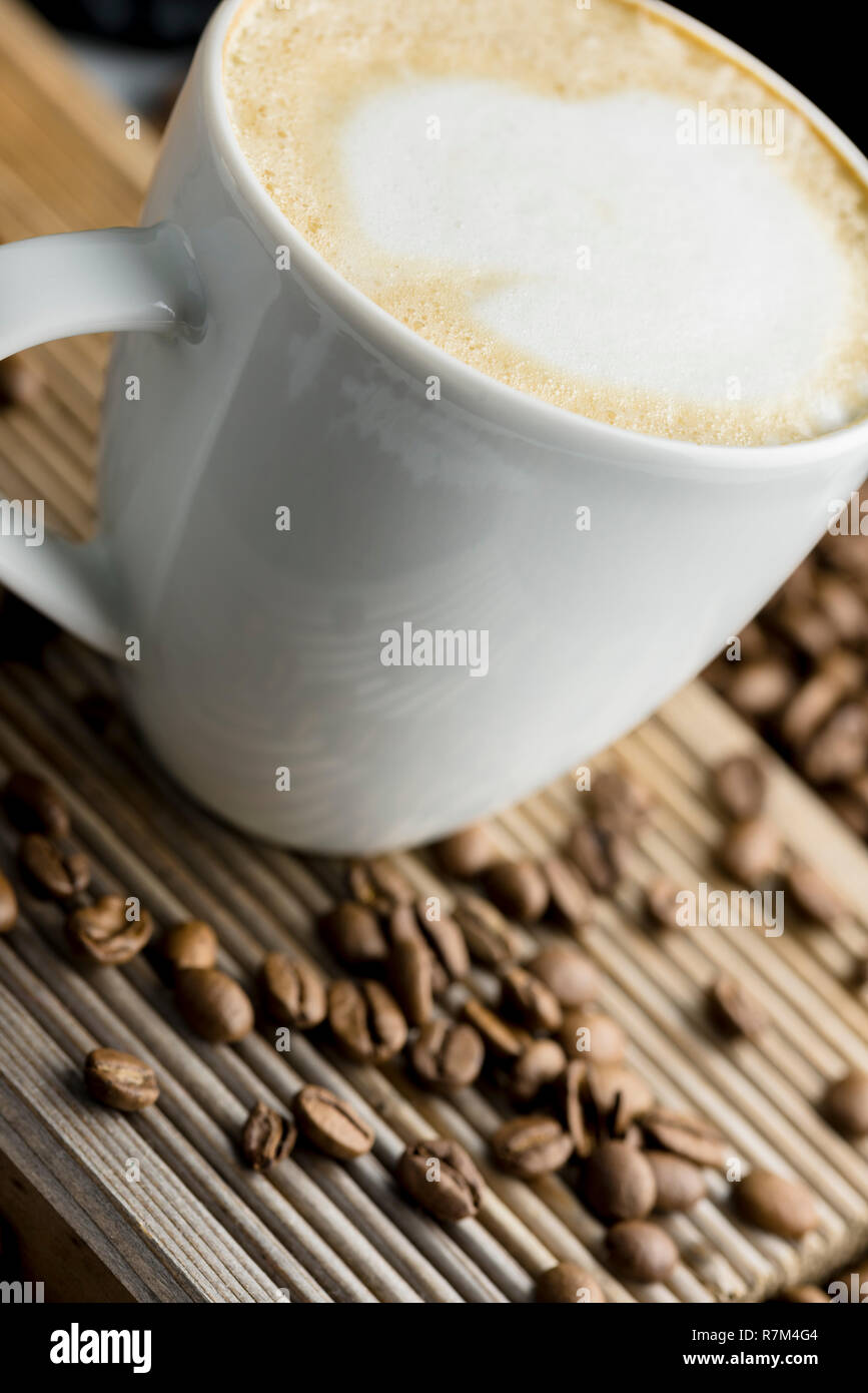 Cup of cafe latte on wooden desk with coffee beans lying around Stock ...