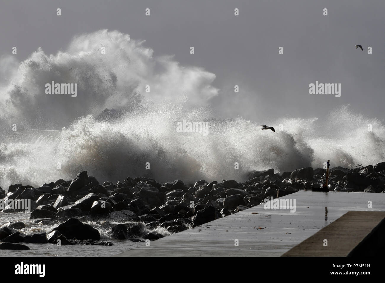 Huge stormy waves passing over the piers and invading the coast Stock ...