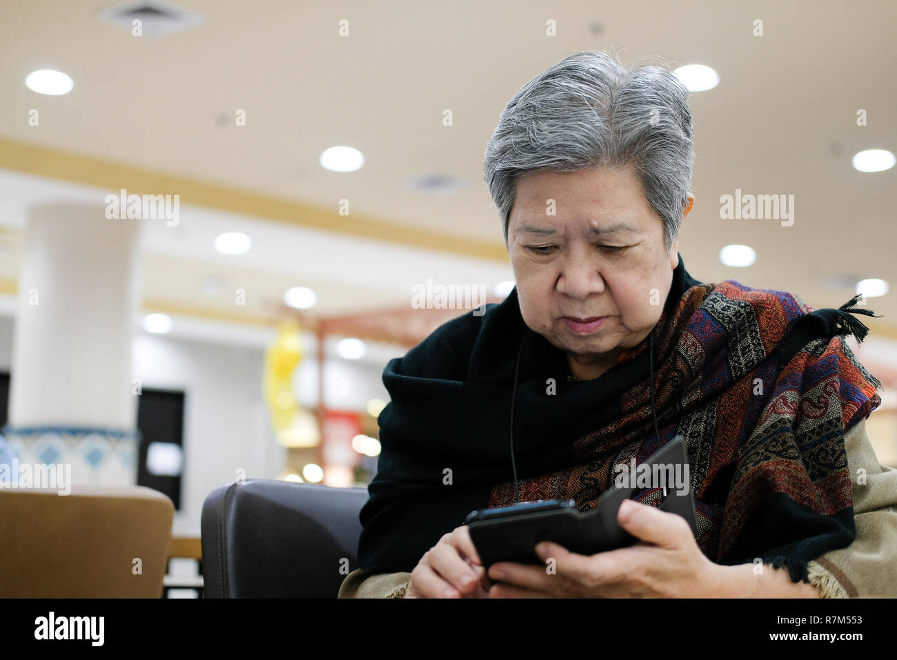 asian elder woman holding mobile phone at restaurant. elderly senior ...