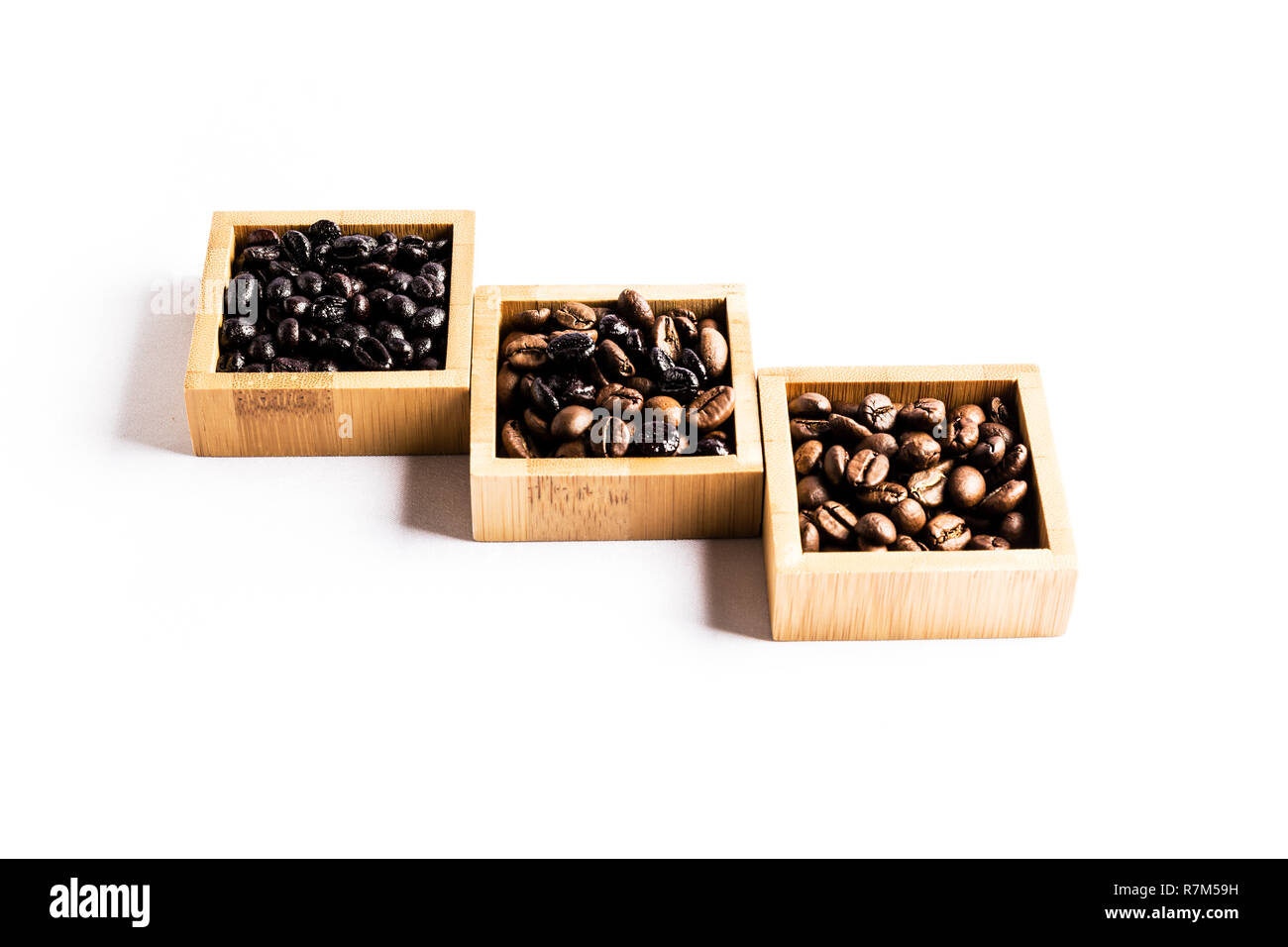 three groups of different coffee beans in wooden bowls on a white ...