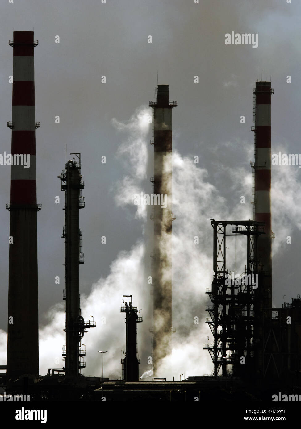 Part of a refinery in a winter day, just befire storm, seeing steam and ...