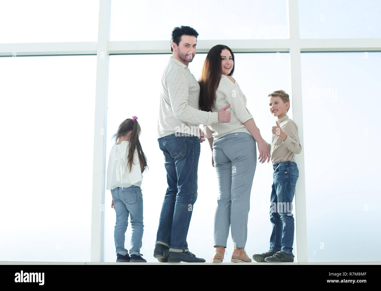rear view.happy family standing by the big window Stock Photo - Alamy