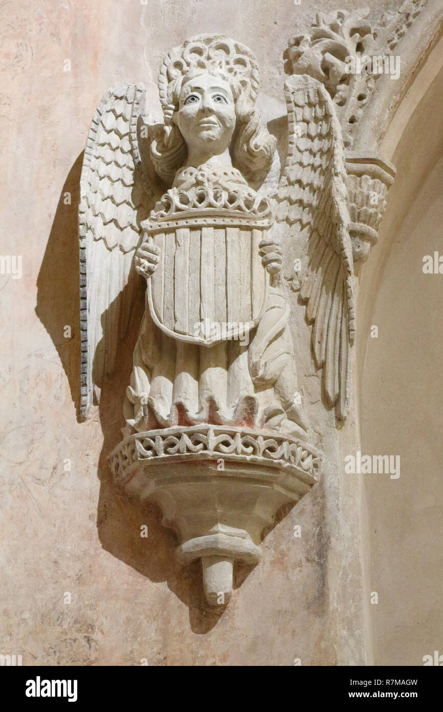 A white stone Romanesque sculpture of the an angel holding the Aragon ...