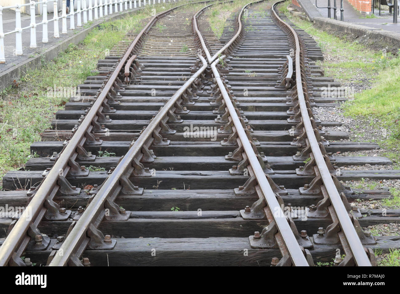 A wet railroad switch among green grass during a cloudy and rainy ...