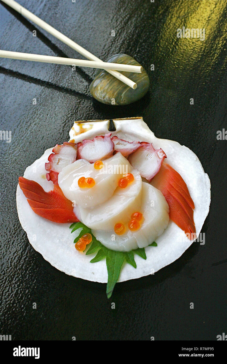 Scallops sashimi is seen served with tuna on a scallop shell. This is a ...