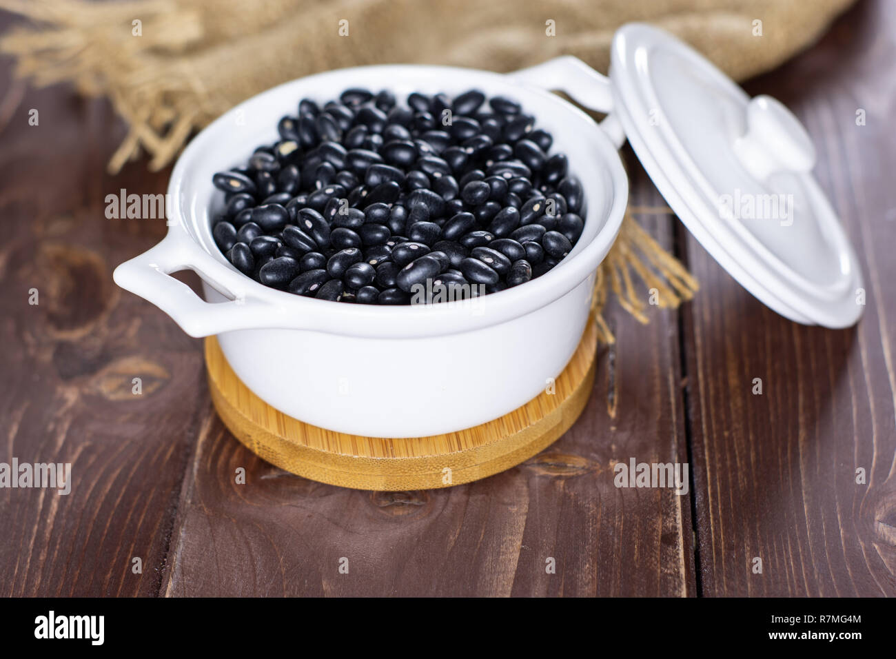 Lot of whole raw black turtle beans in a ceramic stewpan on brown wood ...