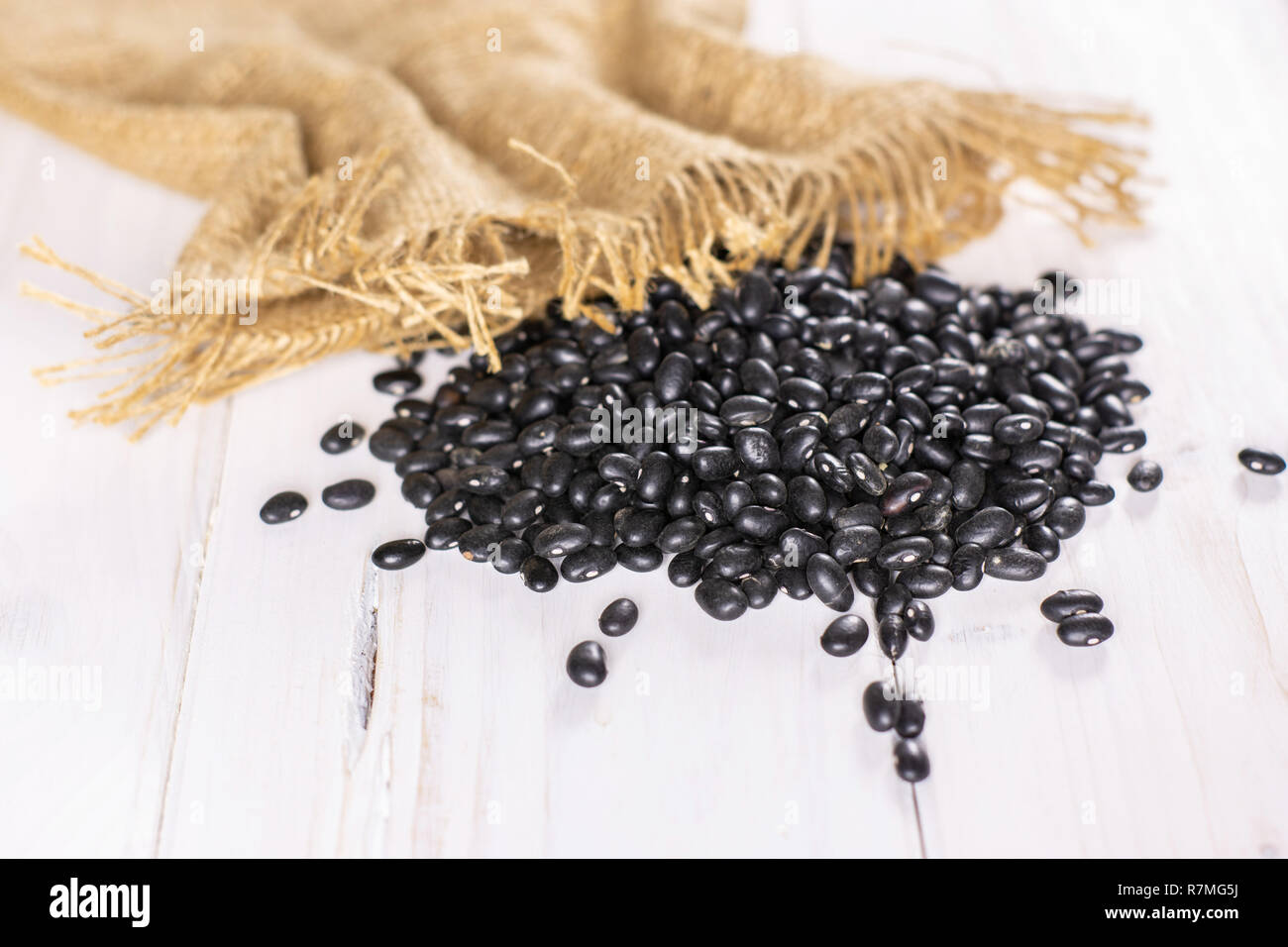 Lot of whole raw black turtle beans on jute cloth on white wood Stock ...
