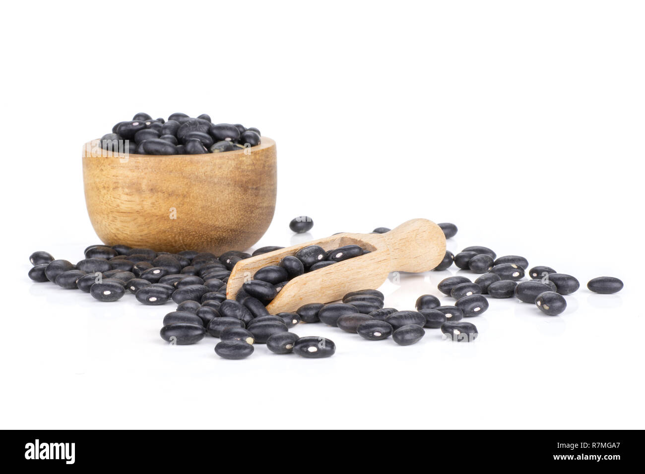 Lot of whole raw black turtle beans in a light scoop with wooden bowl ...