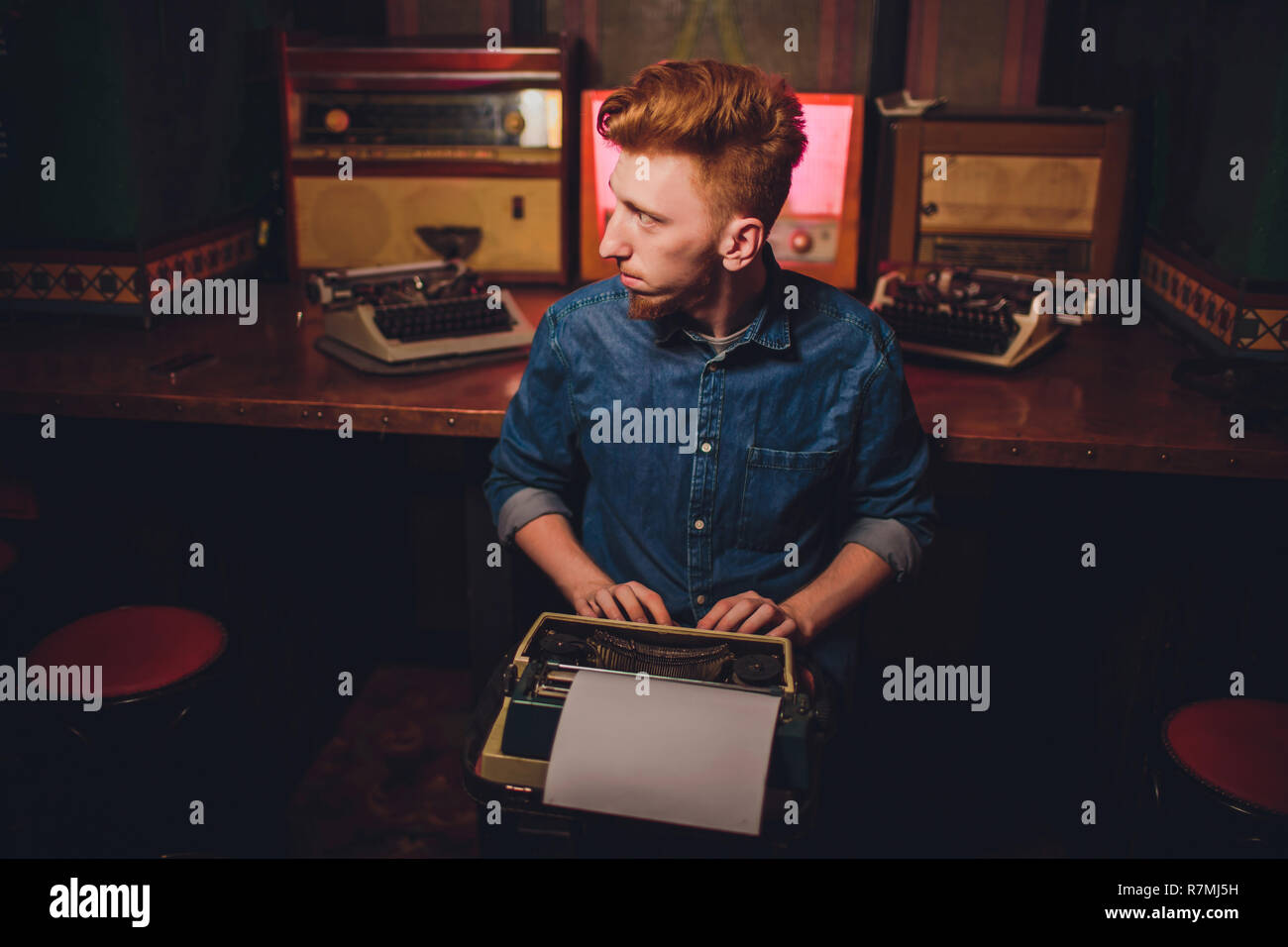 Young man writing on old typewriter. in dark lighting, restaurant ...