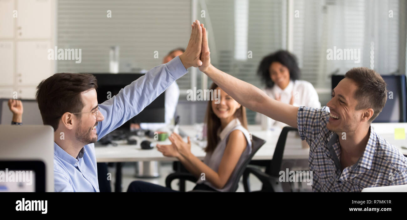 Happy young male colleagues giving high five, celebrate success Stock ...