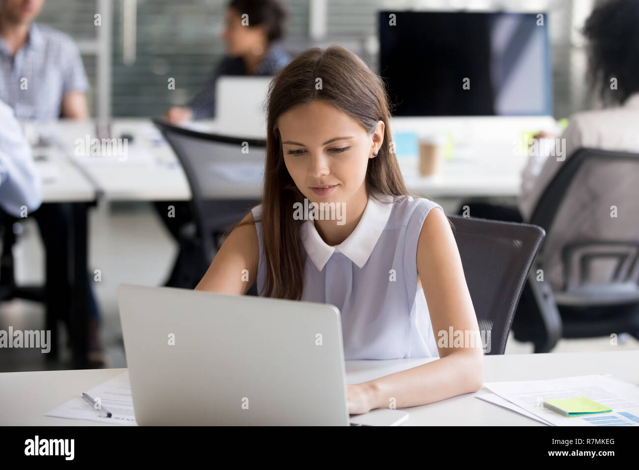 Young girl, intern using laptop at workplace in office Stock Photo - Alamy