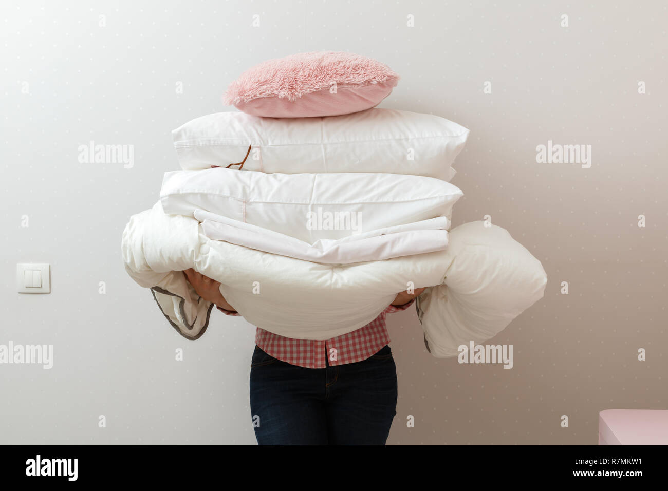 Woman holding a pile of bedding for sleeping Stock Photo - Alamy