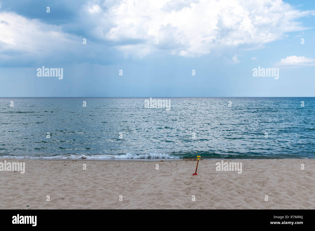 View of the ocean with dramatic clouds and rain on the horizon; a child ...