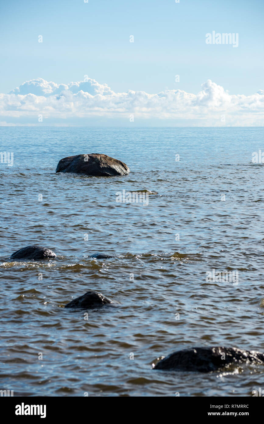 rock covered beach in countryside in Latvia, large rocks in water with ...