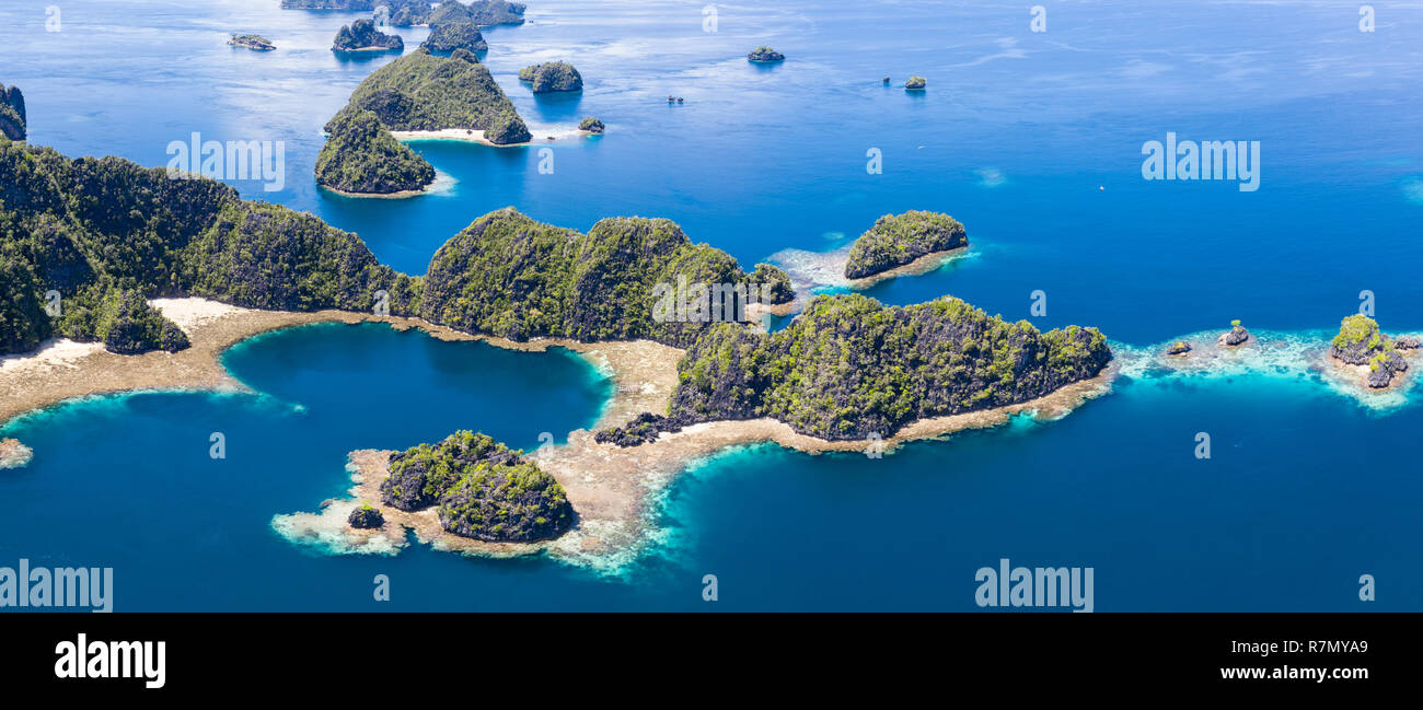 Seen from above, remote islands are surrounded by coral reefs in Raja ...