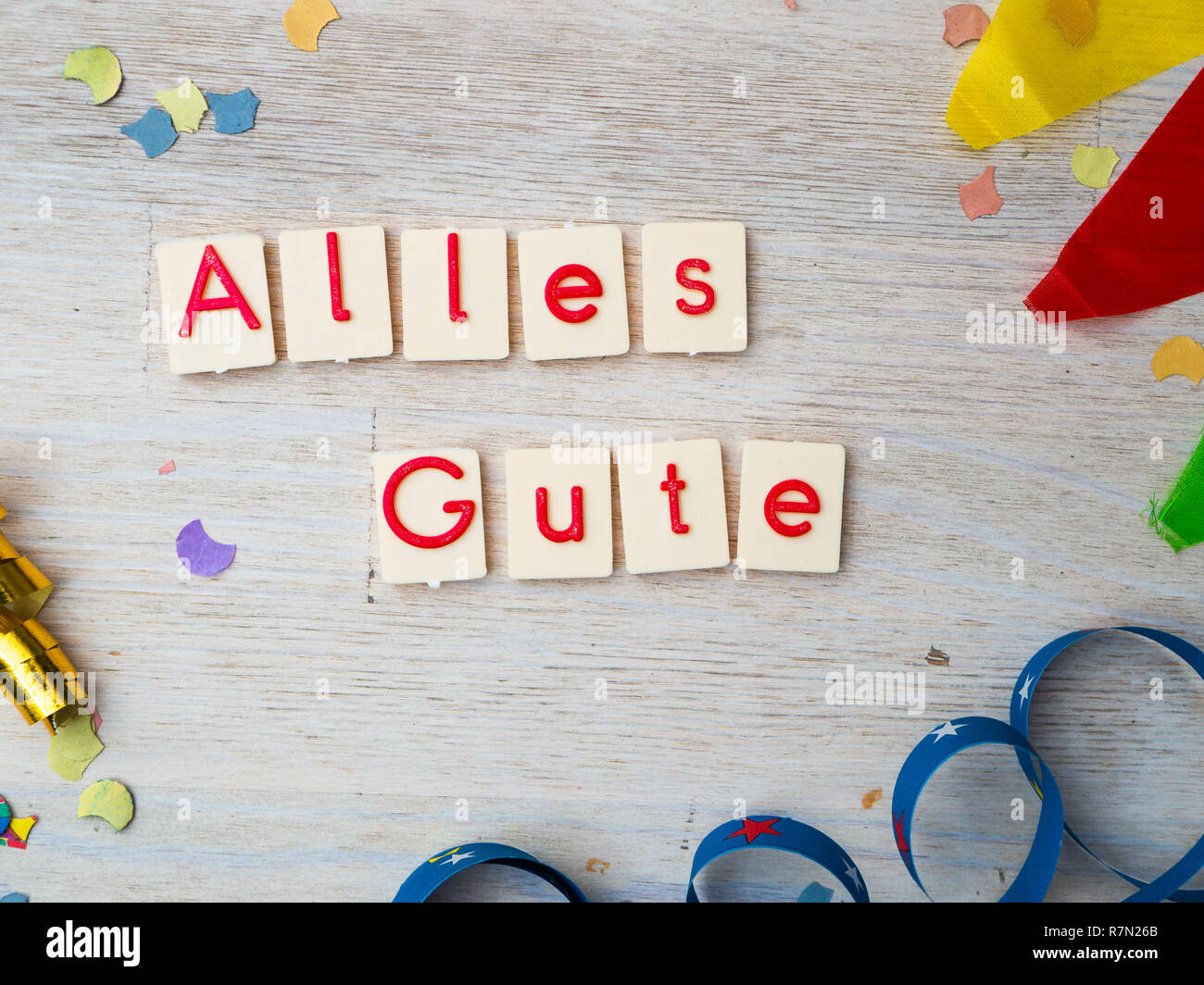 Alles Gute (all the best) lettering with party supplies on wooden ...