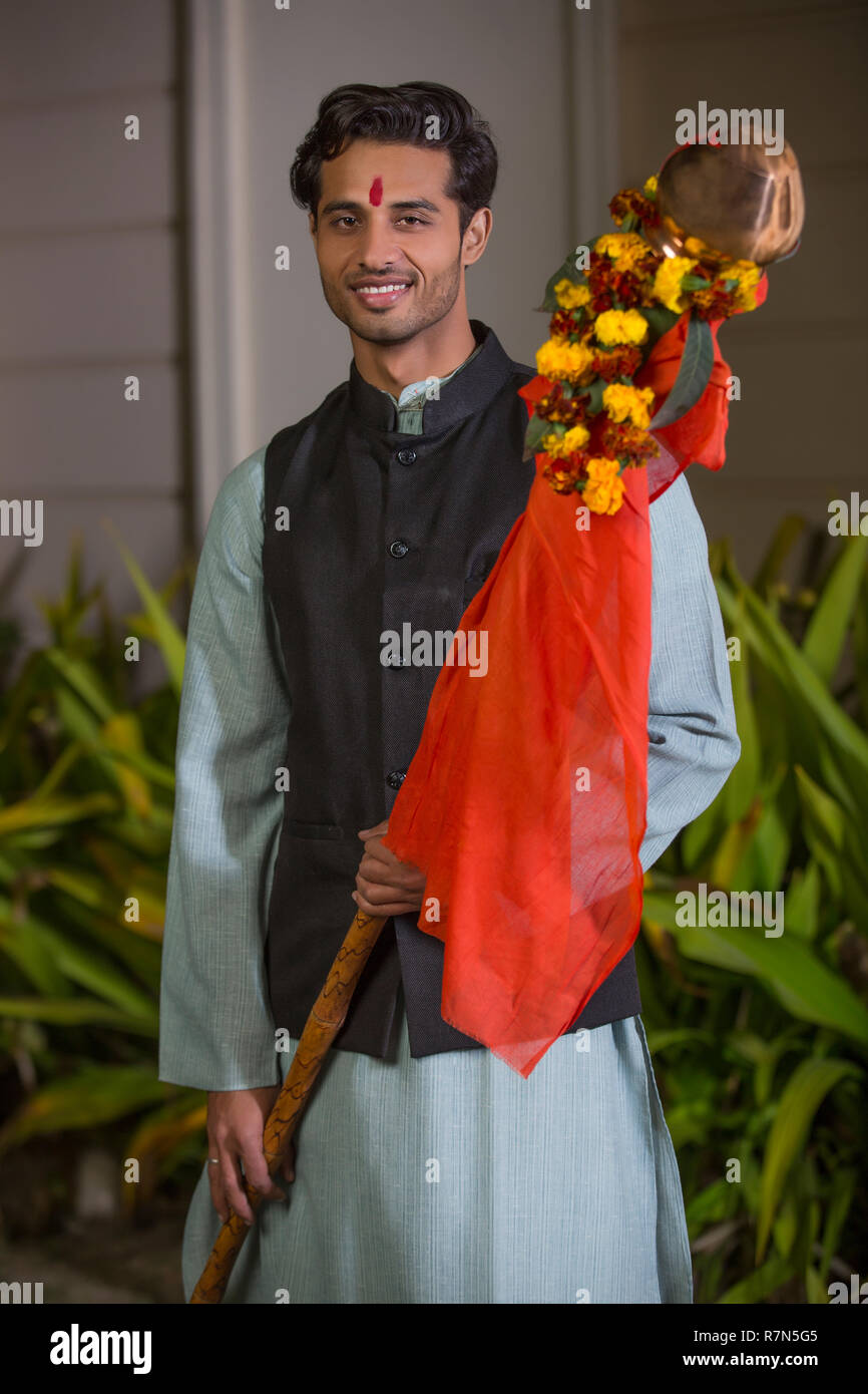 Smiling maharashtrian man in traditional dress holding the gudi while ...