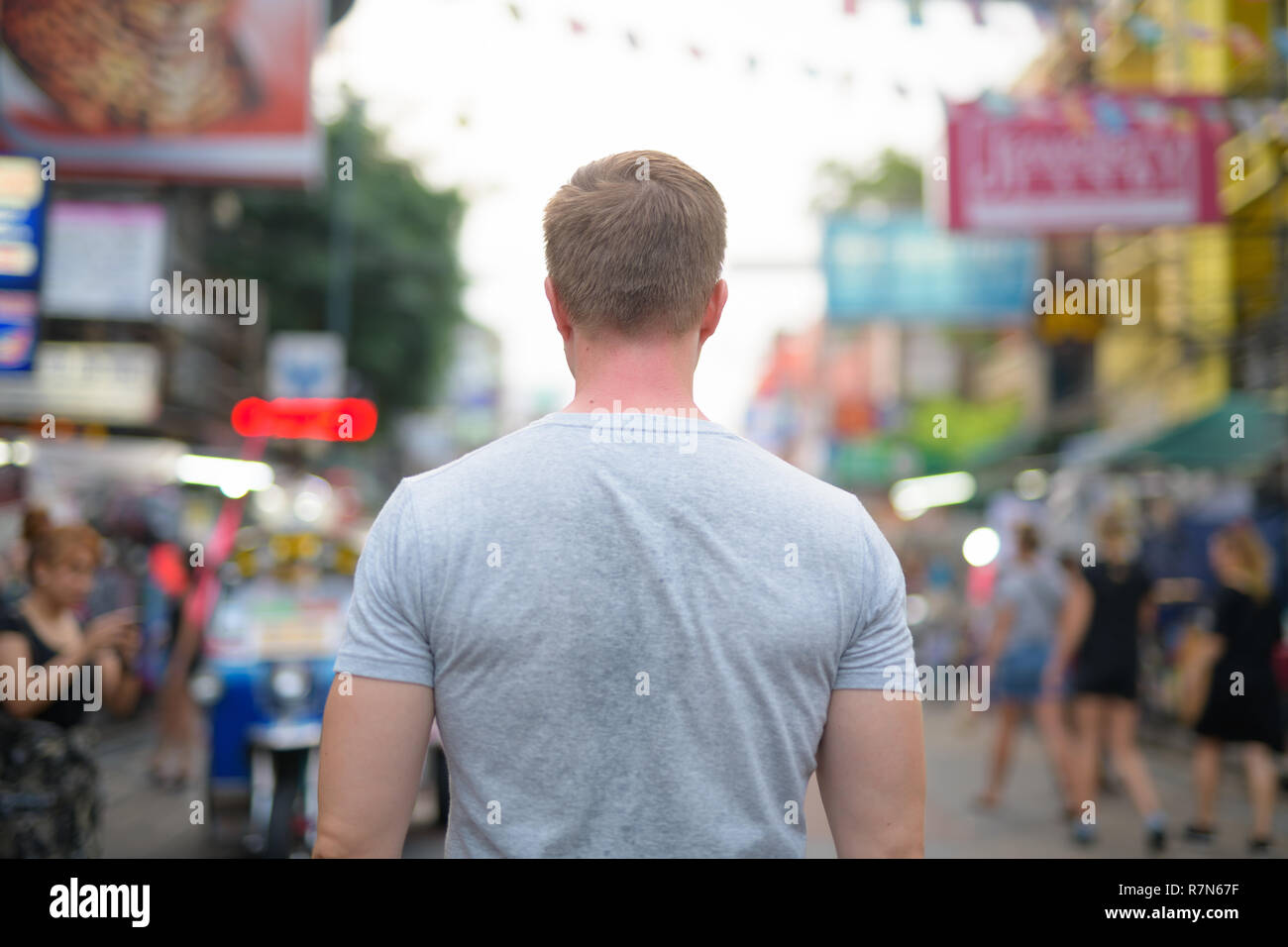 Rear view of young tourist man against view of Khao San road in Bangkok ...