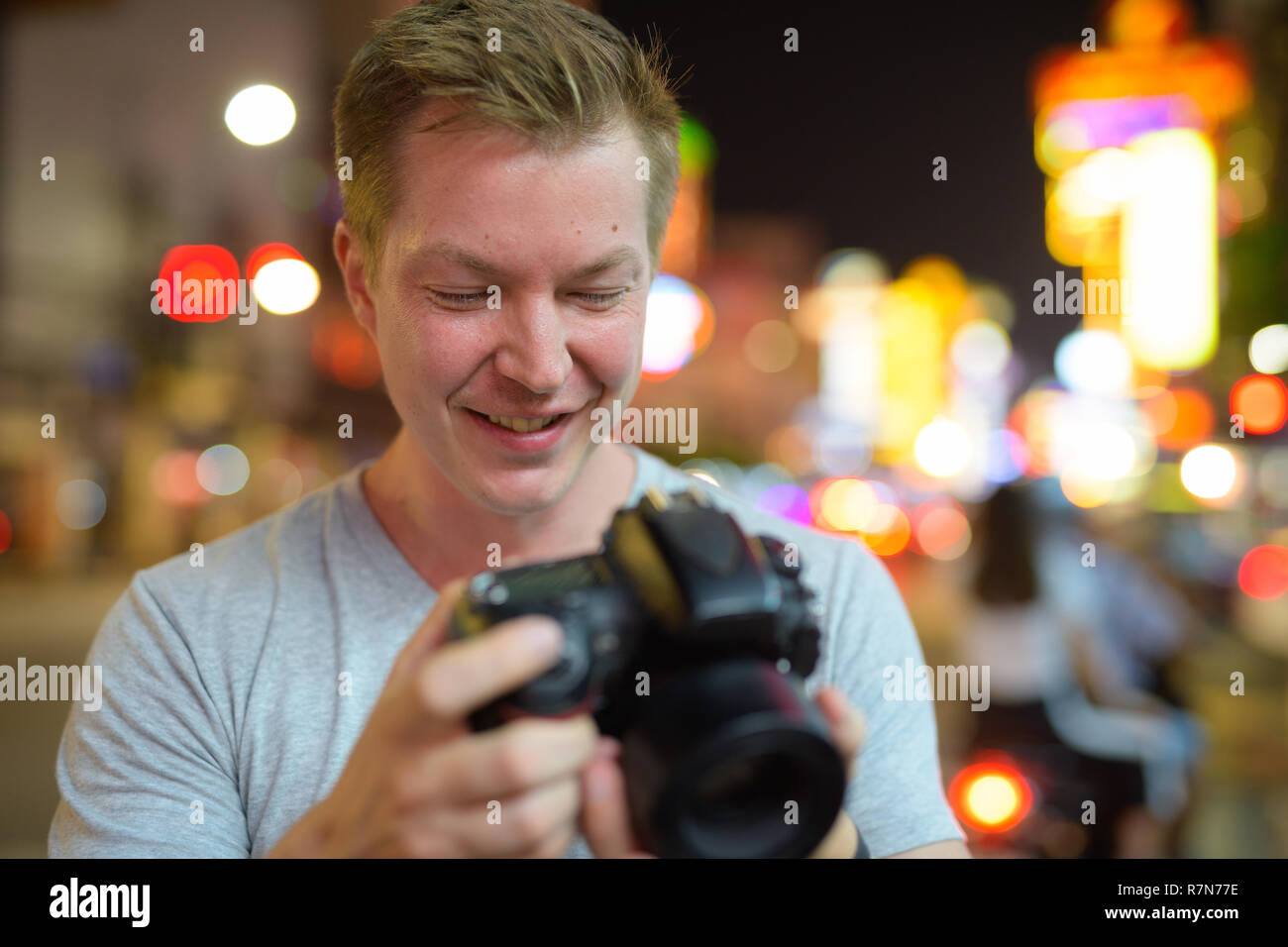 Face of young happy tourist man checking camera in the streets of ...