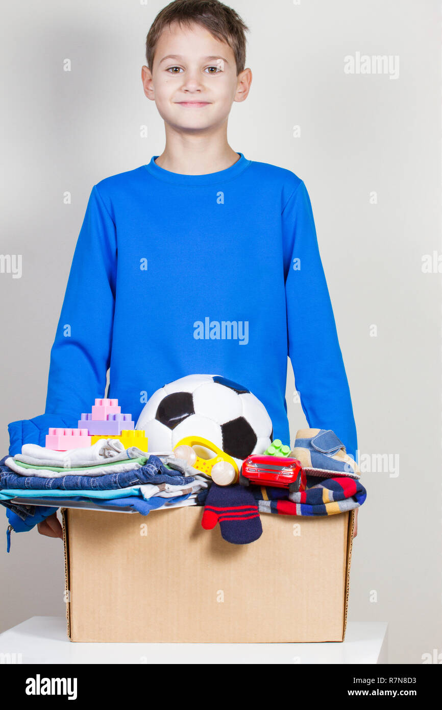 Donation concept. Kid holding donate box with clothes, books and toys ...