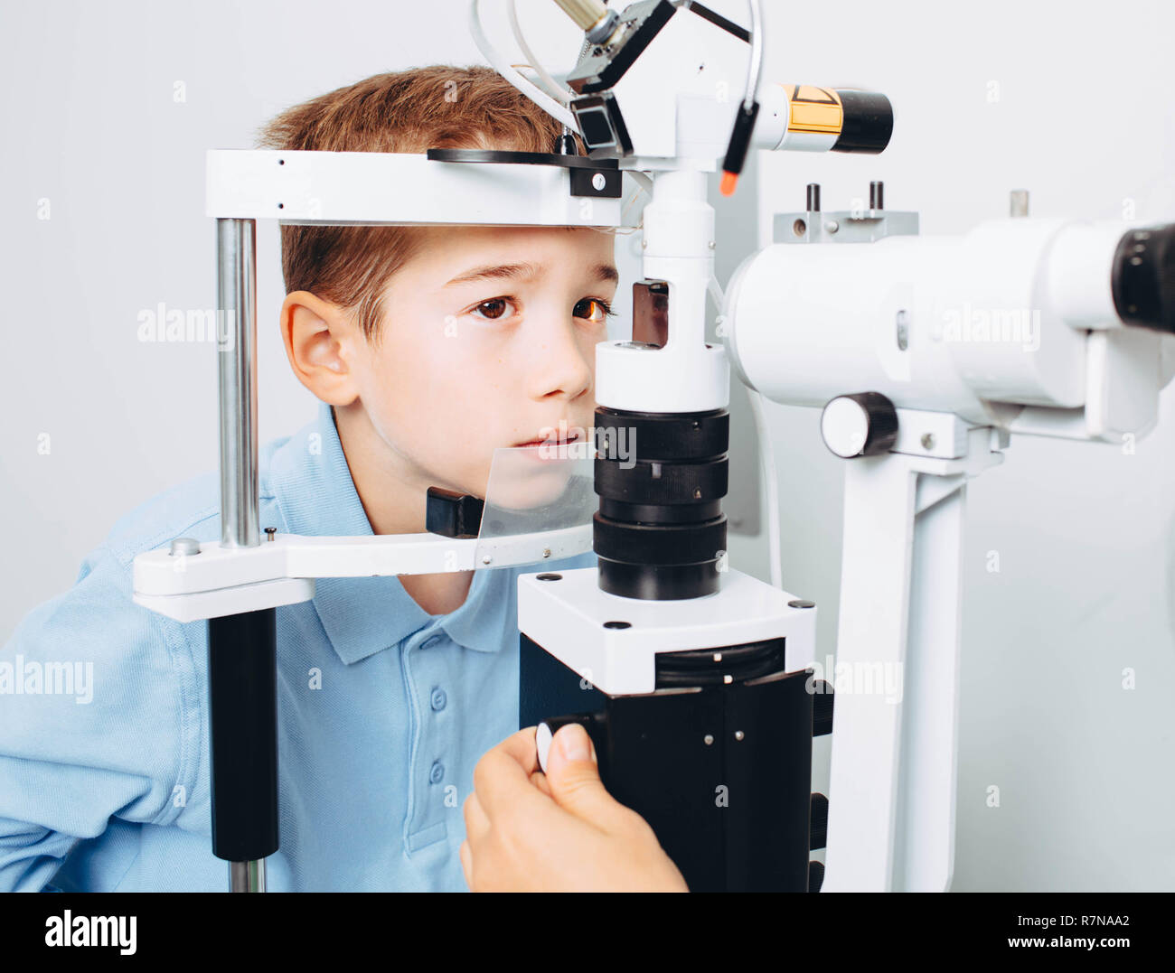 optometrist making an eye test to little cute boy at clinic Stock Photo ...
