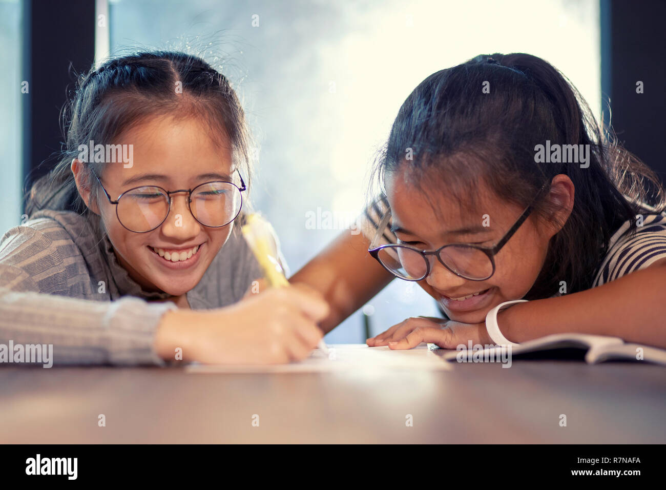 asian teenager writing by pen on white paper and toothy smiling with ...