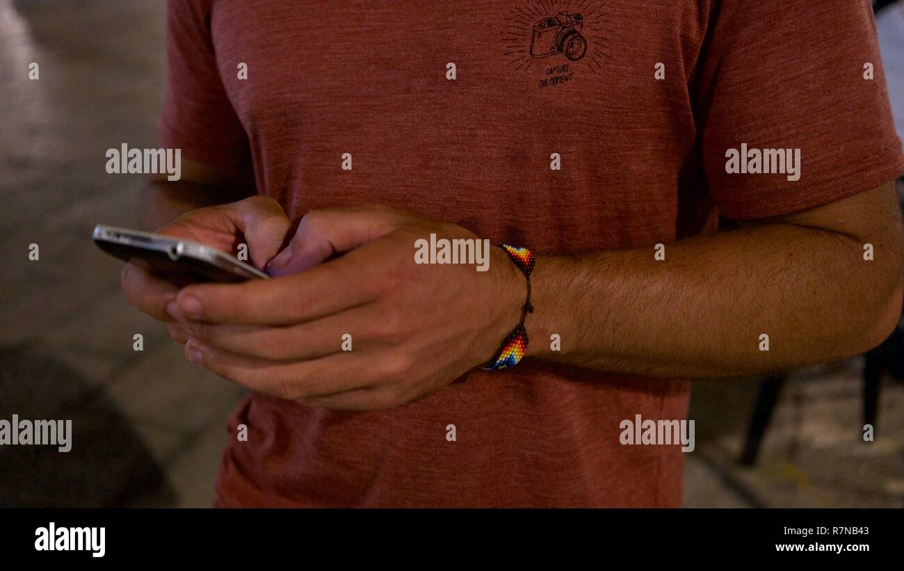 A young caucasian man using his phone in a plaza Stock Photo - Alamy