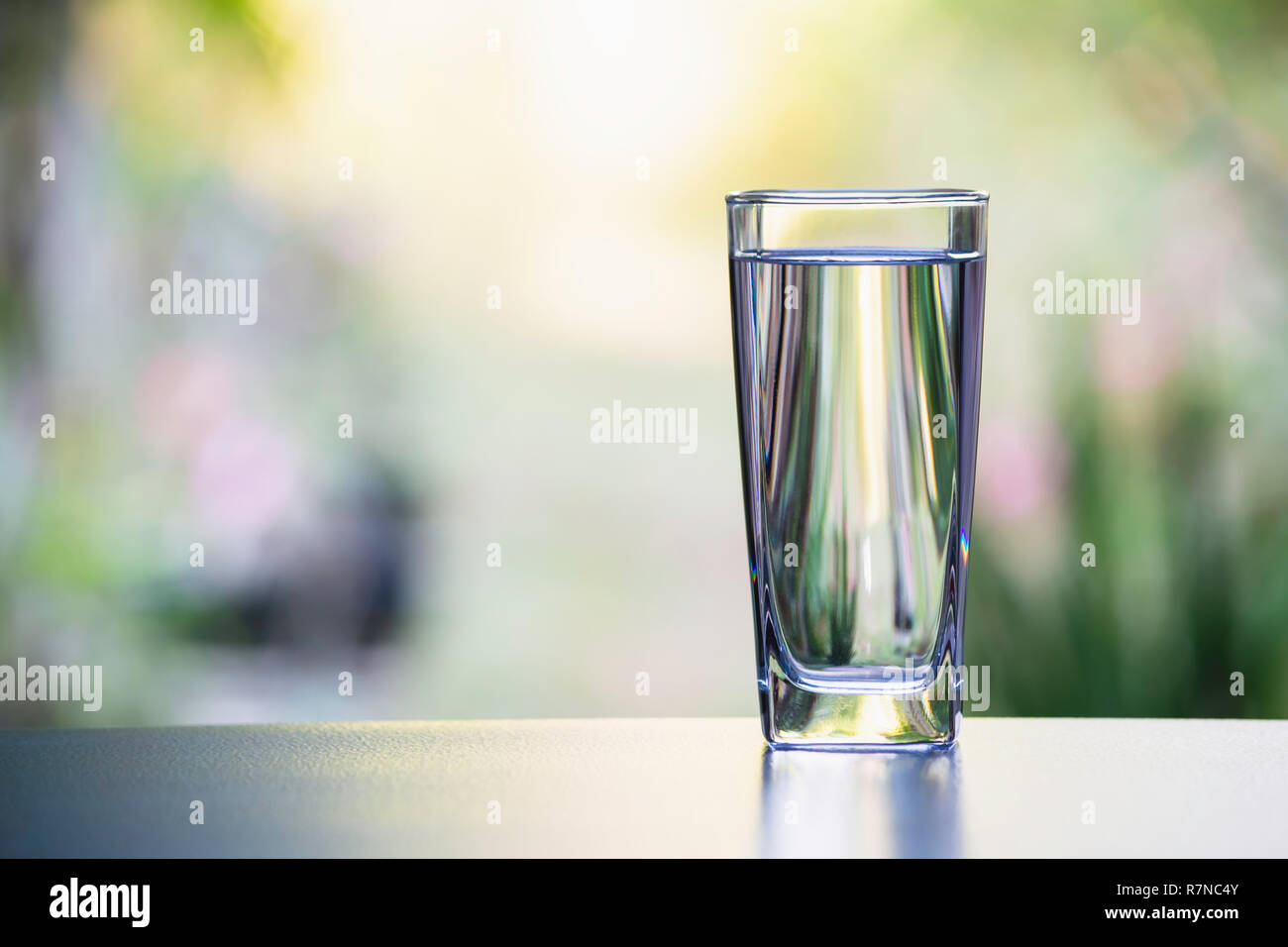 Water in the glass on table with nature background Stock Photo - Alamy