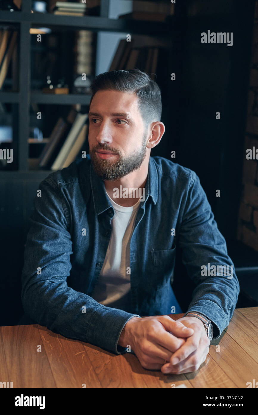 Young man sitting in a cafe at the table and waiting for the waiter ...