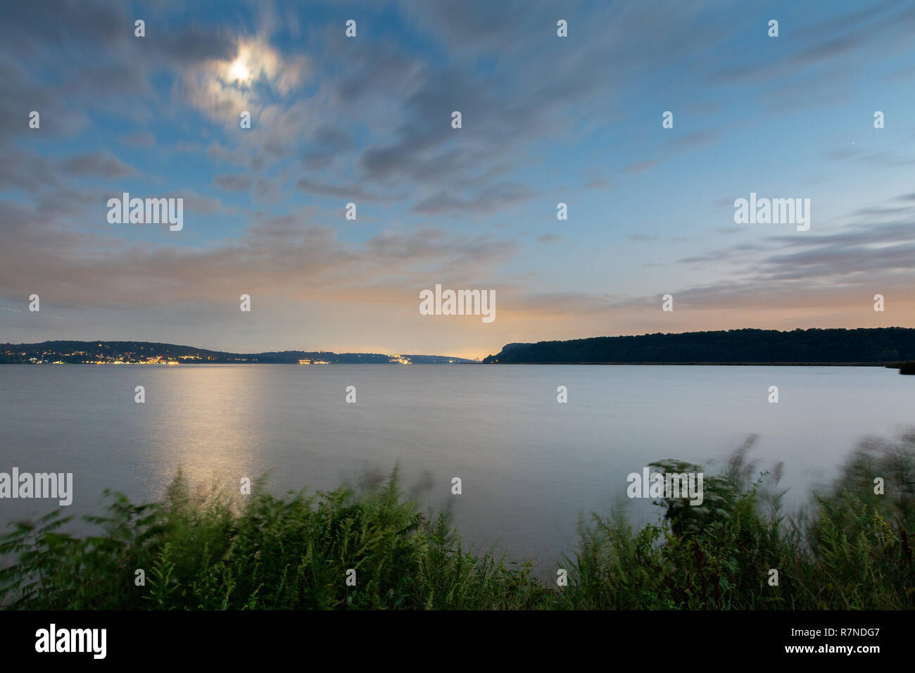 The moon shining from behind a cloud above the Hudson River and the ...