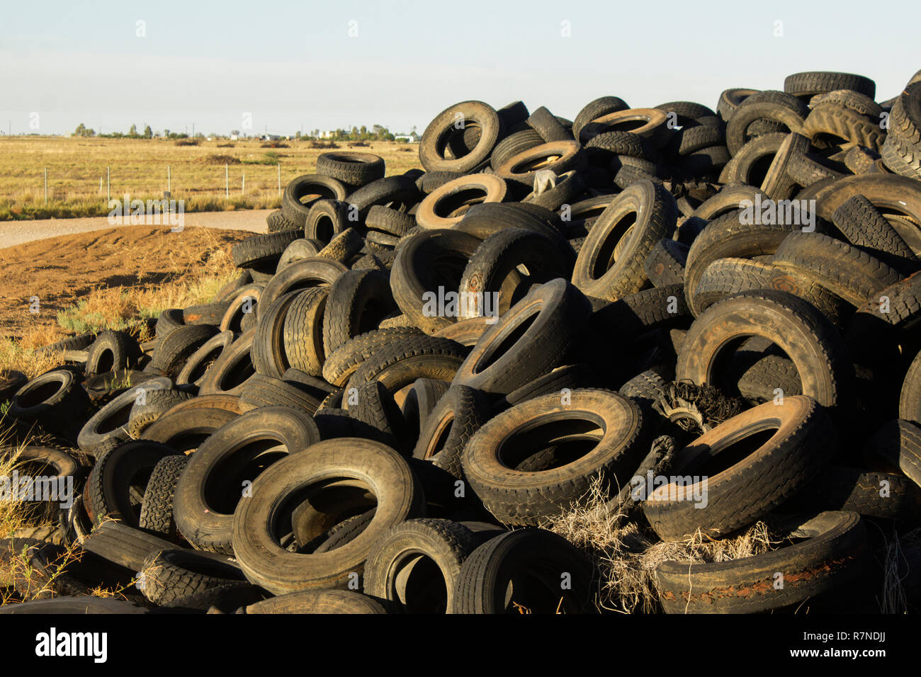 Pile of discarded car tyres in country rubbish dump with open paddock ...