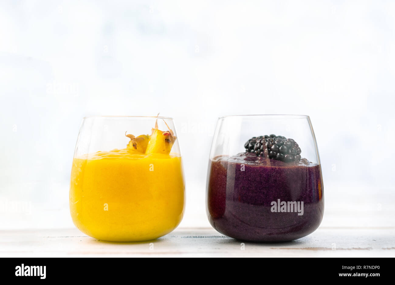Colorful detox yellow and blue smoothie in two glasses on white ...